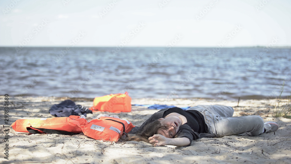 Body of dead woman lying on seashore near life jackets, shipwreck ...