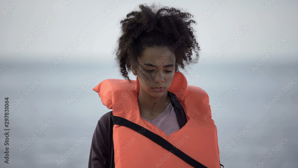 Sad teenage girl in life jacket looking distressed and lonely, disaster ...