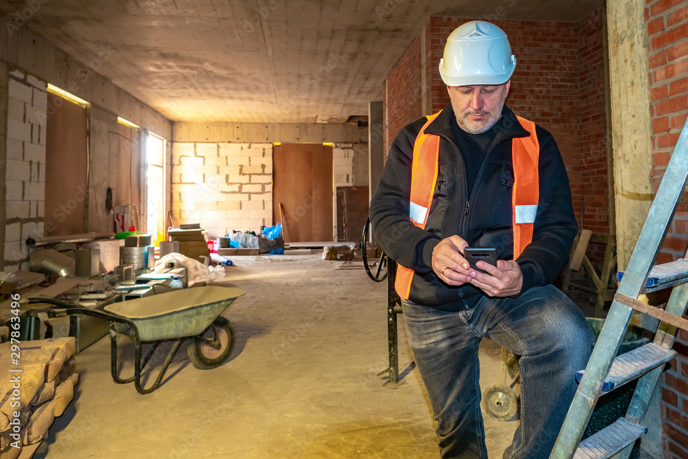 A man at a construction site. Work as a builder. Builder with phones in ...