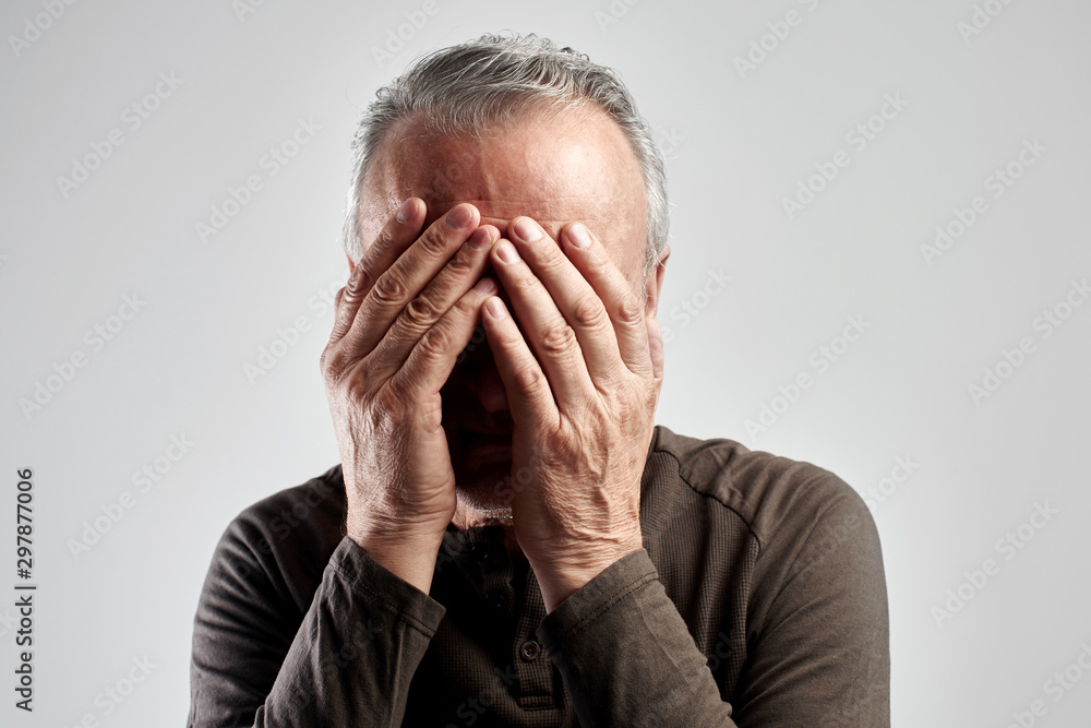 Portrait of senior citizen man covered his face with hands isolated on ...