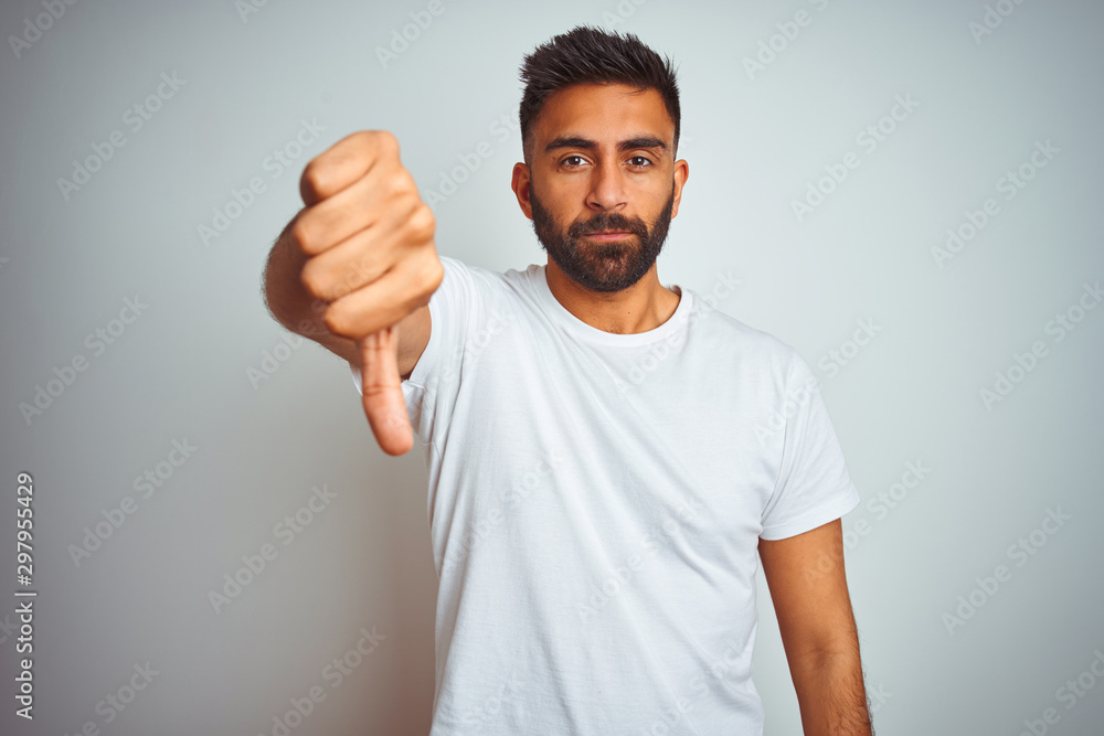 Young indian man wearing t-shirt standing over isolated white ...