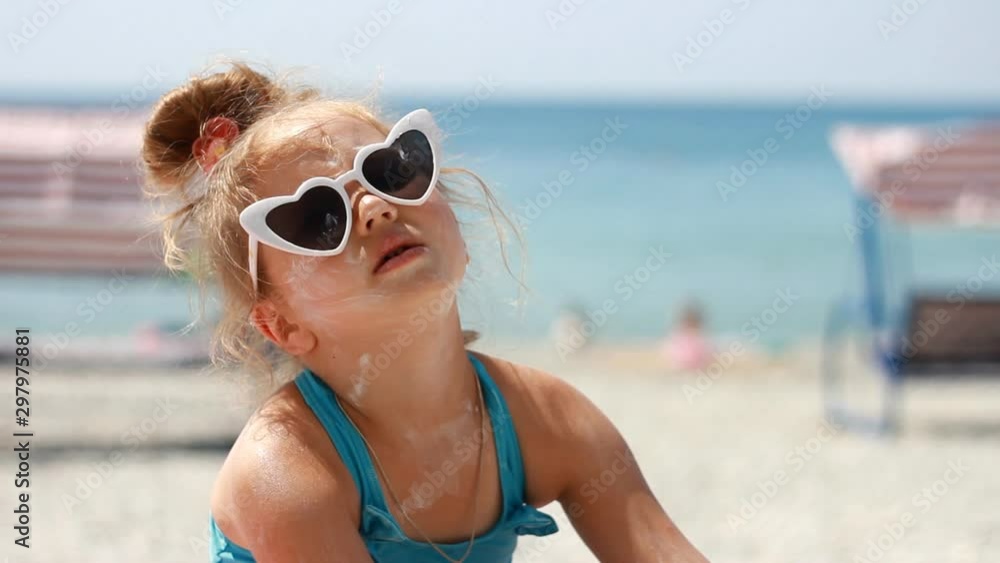 Baby girl smearing sun cream fase and body. Sunburn. Suncream cream ...