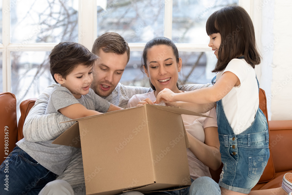 Curious happy family holding big carton box, unpacking delivery parcel ...