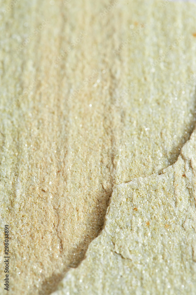 Grainy texture of yellow-beige raw slate with a chip in the lower right ...