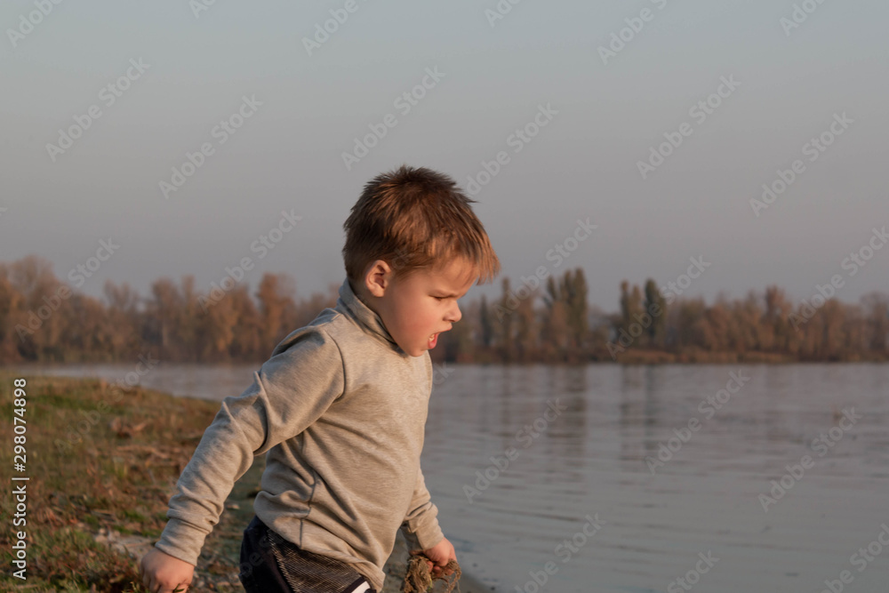 Little boy child angry, nervous, annoyed on the beach near the lake ...
