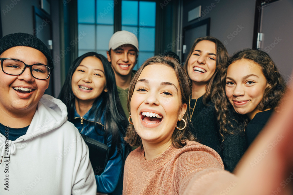 Cheerful teenage classmates taking selfie in corridor Stock Photo ...