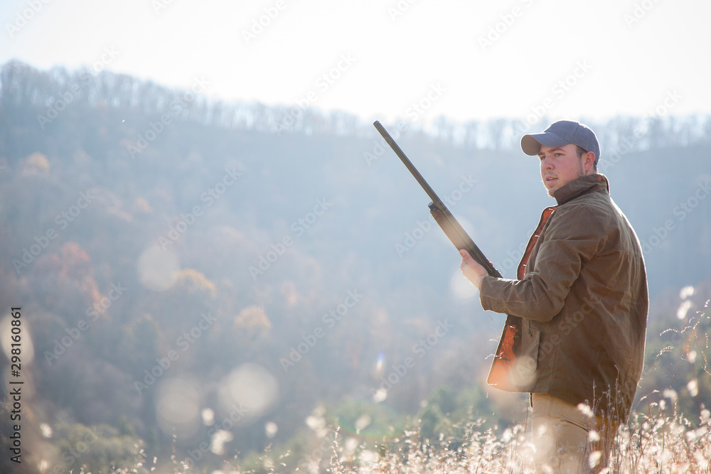 Young man holding rifle in field Stock Photo | Adobe Stock