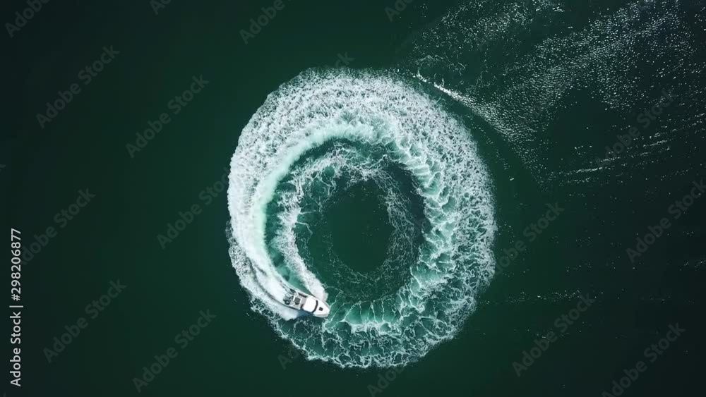Aerial bird view of a speedboat riding in a circle and making beautiful ...