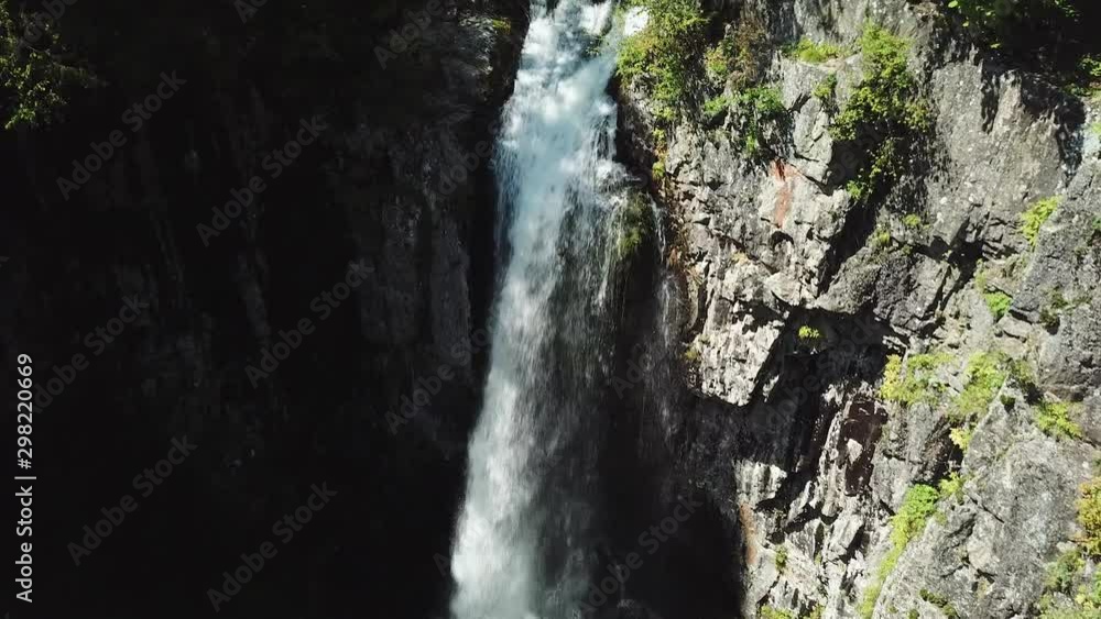 Grand high waterfall full stream cascaded down cliff. Sun shines bright ...