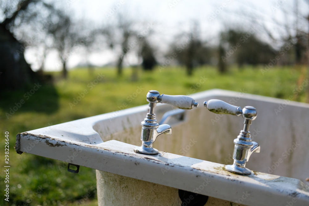 Old, abandoned ceramic bath and chrome water taps as seen in a field ...