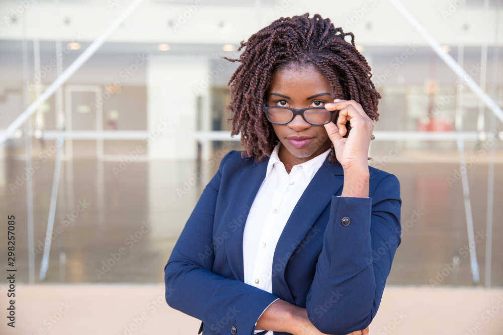 Foto de Serious female office employee touching eyewear outside. Young ...