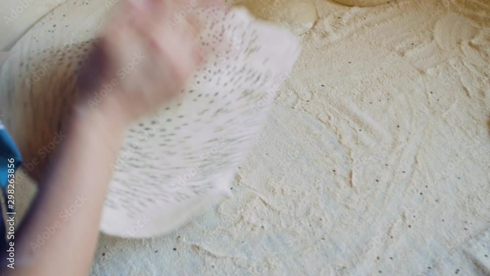 Handheld shot of a person clapping and forming a piece of the dough, to ...
