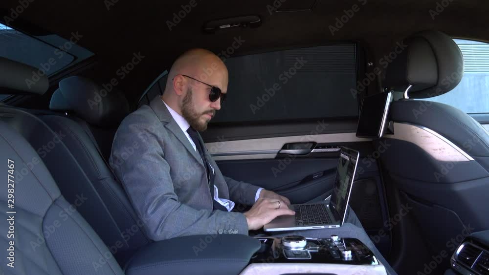 Vidéo Stock Handsome businessman sitting with laptop on the backseat of ...