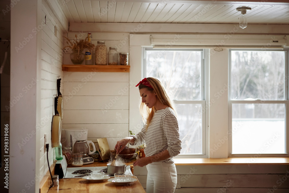 Side view of woman cooking food in kitchen Stock Photo | Adobe Stock