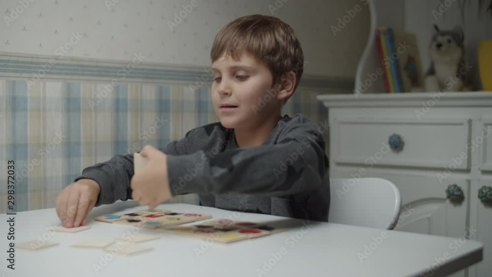 Autistic kid completing puzzle on the table in slow motion. Child with ...