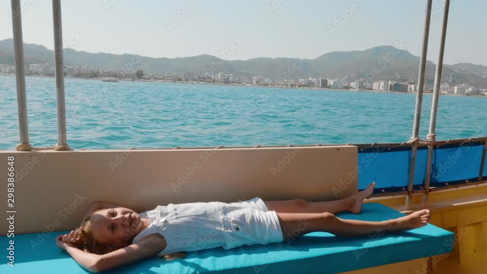 Tourist girl relaxing on floating yacht at sea walk. Young girl lying ...