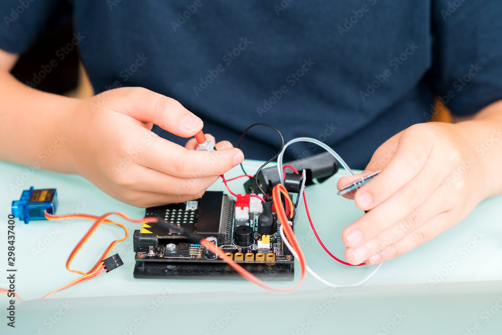 Closeup of a child's hands working with circuits, wires, computer chip ...