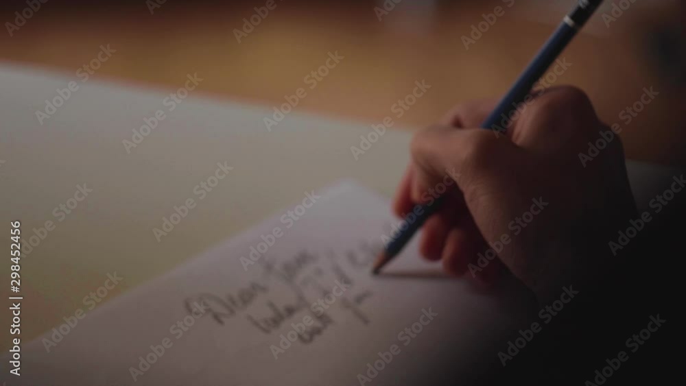 close up su mano che scrive una lettera con una matita su un foglio di ...
