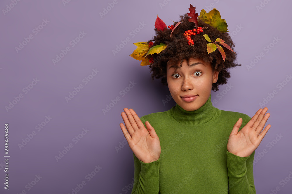 Confused curly female raises palms, shows being uninvolved, gestures in ...