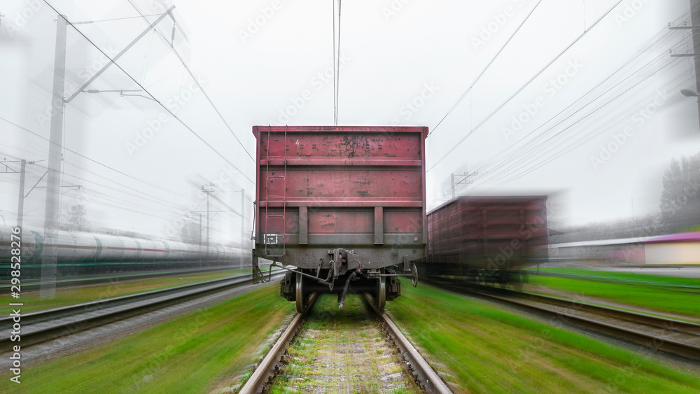 Freight train goes by rail. Back view. Blurred background gives a ...