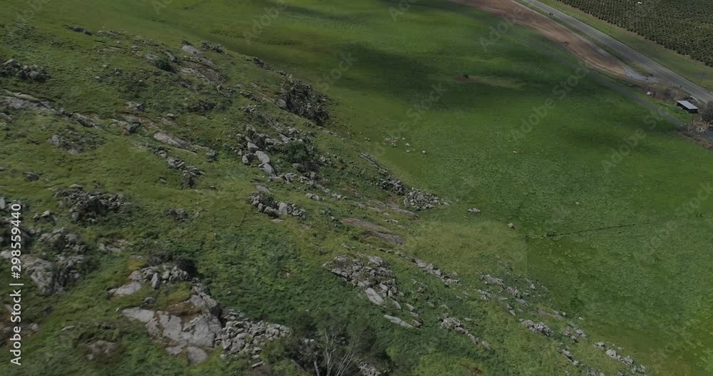 Pan up from green hillside to reveal country road and farm lands with ...
