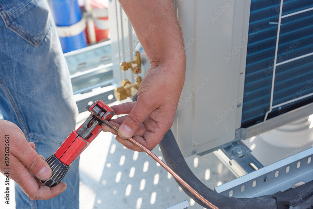 HVAC technician is working on air conditioner units on a roof of new ...