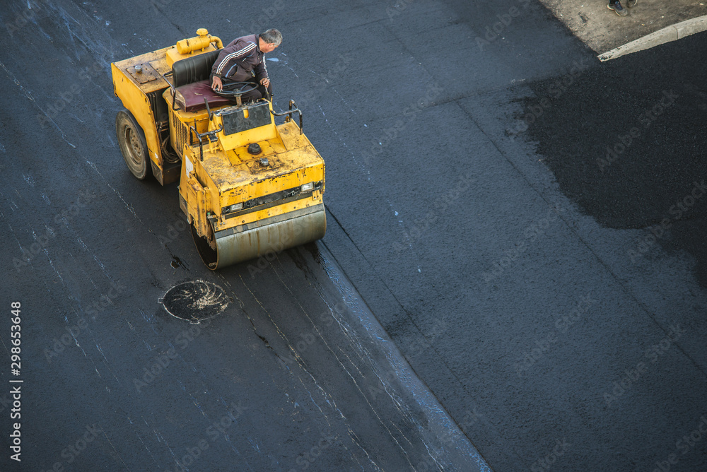 Workers lay a new asphalt coating using hot bitumen. Work of heavy ...
