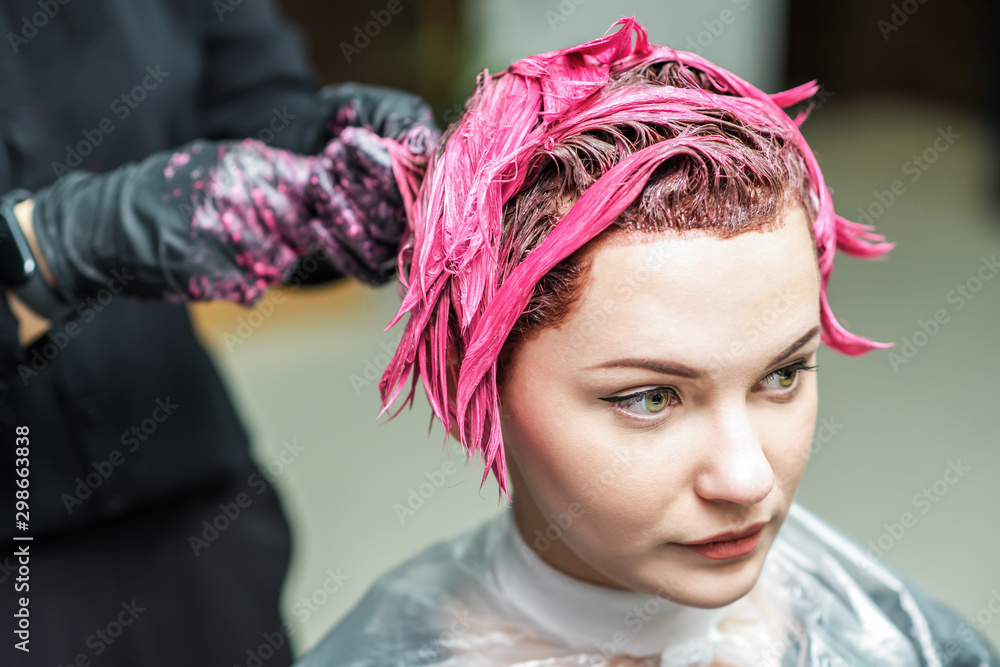 Hairdresser's hands are applying pink color to customer's hair. Hair ...