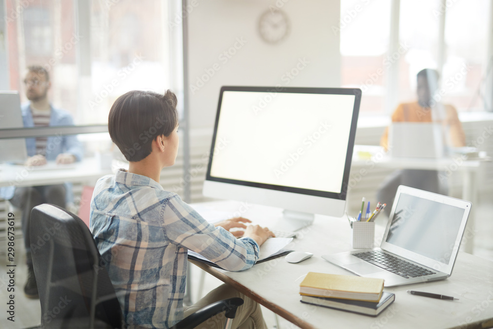 Back view portrait of modern young woman using computer in office ...