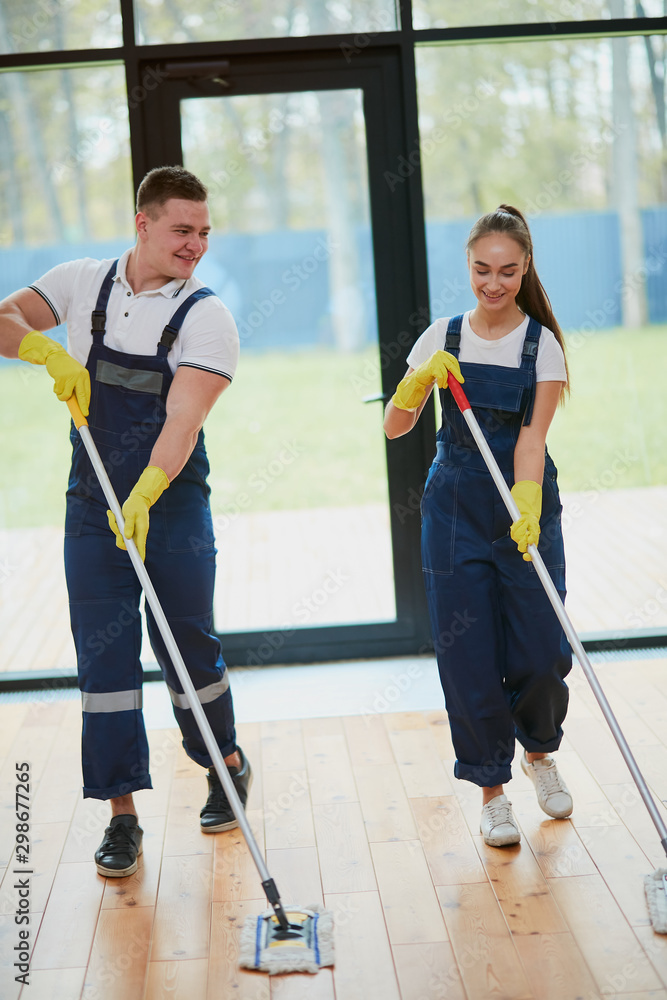 Two coleagues of cleaning company cheerfully cleaning new house ...