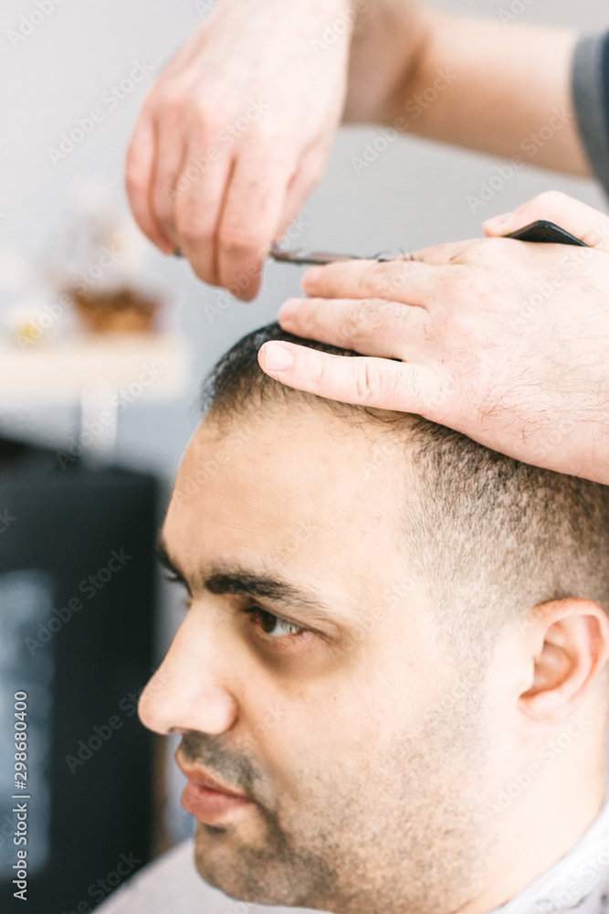 Barber making stylish haircut with professional scissers in barber shop ...