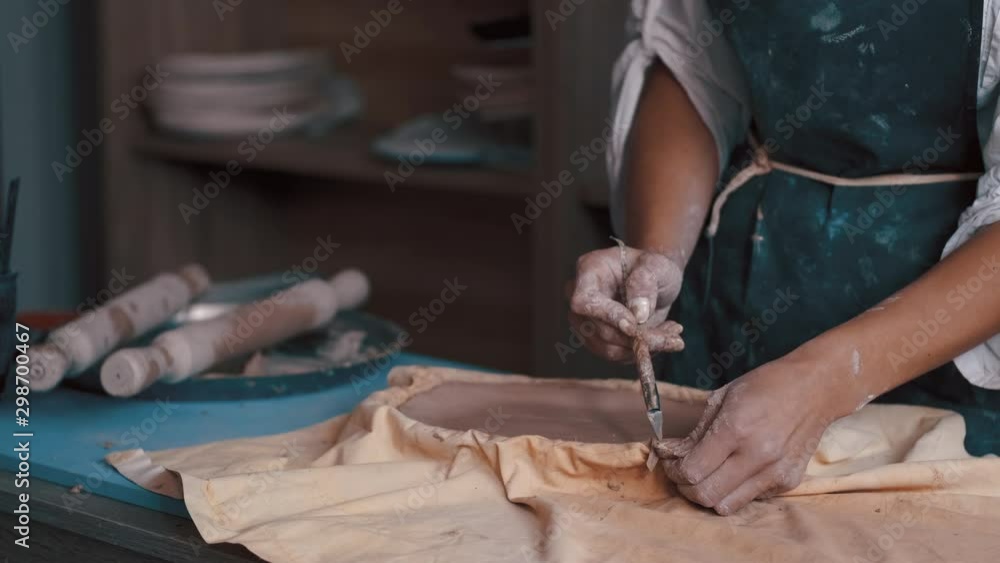 potter forming clay into a dish by using a form and tools to get the ...