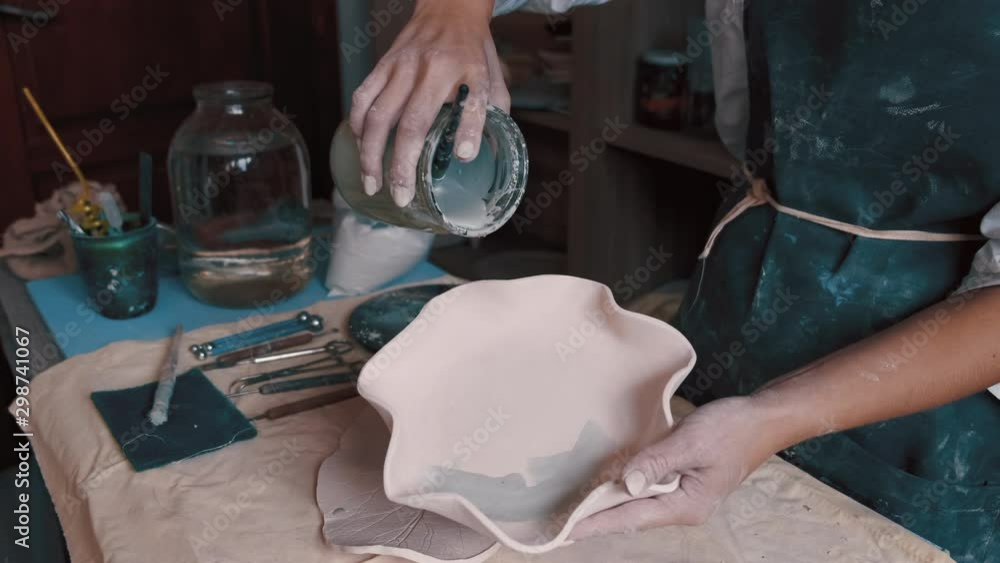 professional potter decorating and painting a dish after she has baked ...