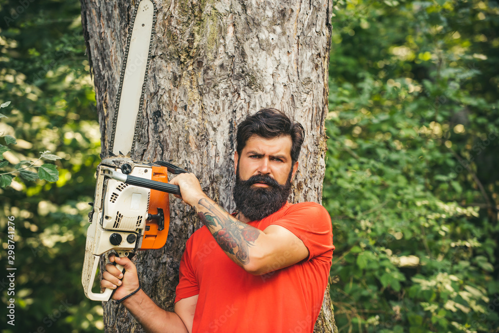 Lumberjack worker standing in the forest with chainsaw. Deforestation ...