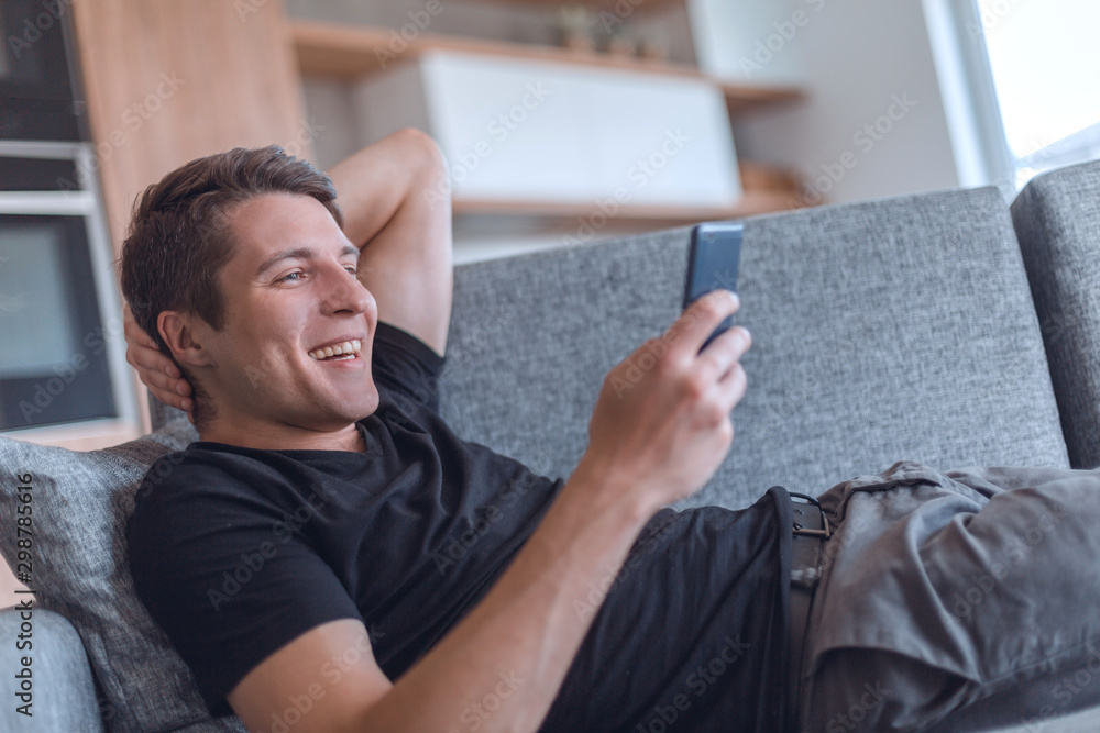 beautiful young man lying on the couch in his living room Stock Photo ...