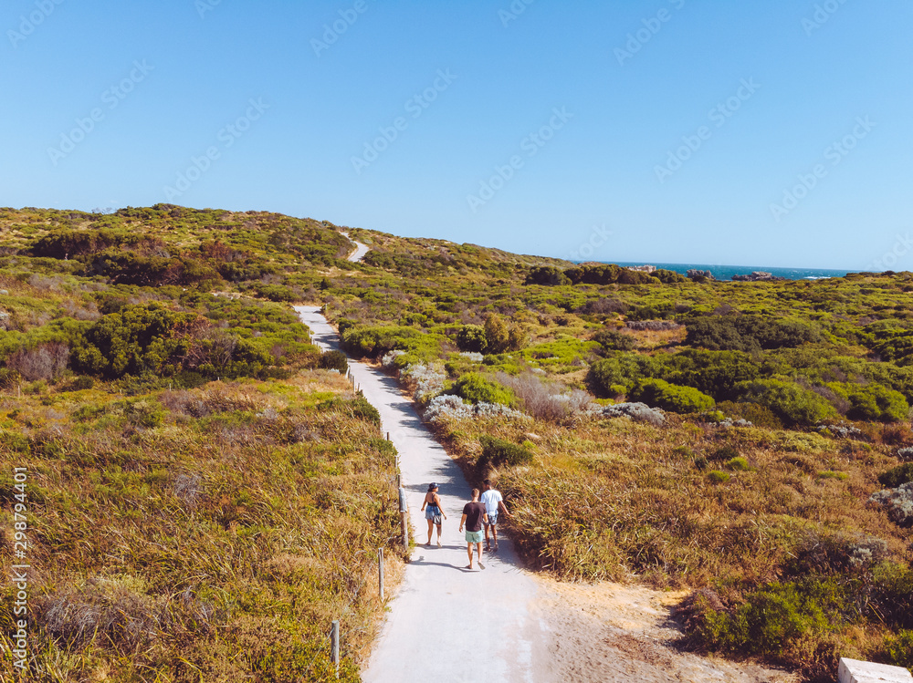 People walking along a path through the shrubs and dunes towards the ...
