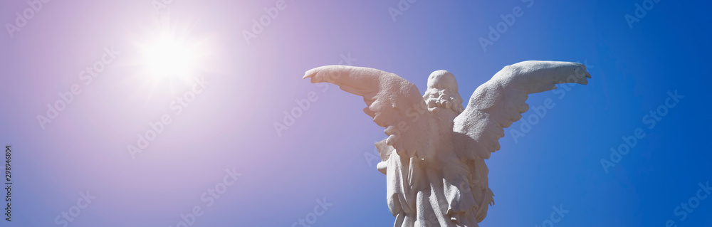Rear view of antique statue angel in sunlight as a symbol of strength ...