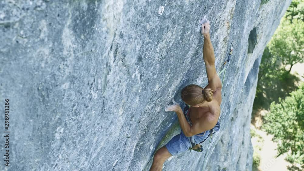 strong muscular tanned man rock climber climbing on a limestone cliff ...