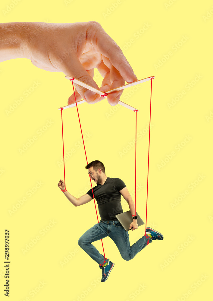 Man like a puppet in somebodies hands on yellow background. Concept of ...