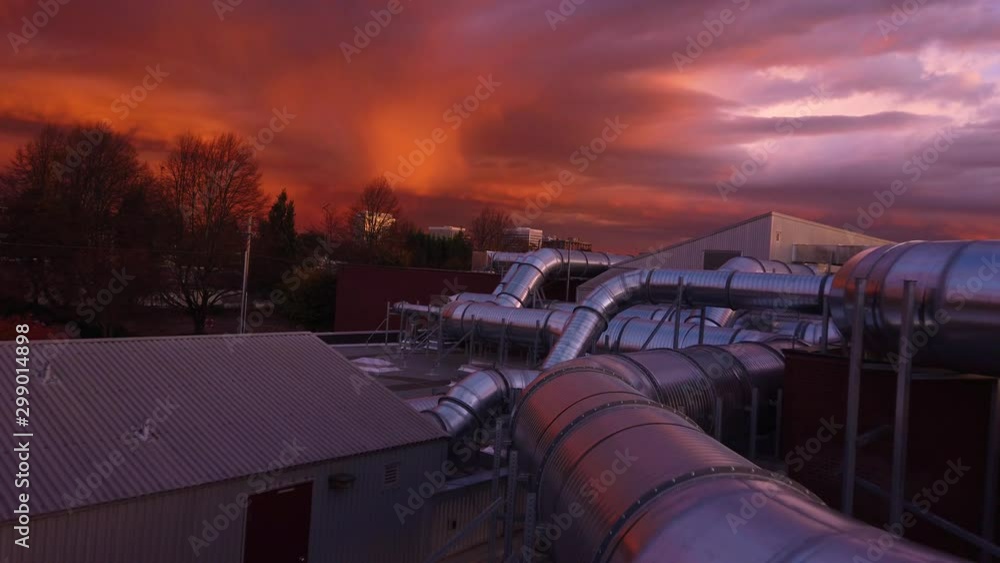 Drifting over HVAC ducts toward an orange stormy sunset sky with a mob ...