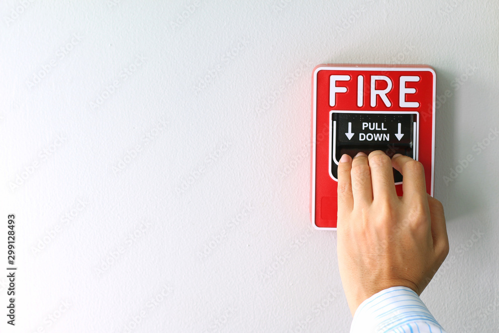 Hand of woman pulling fire alarm switch on the white wall as background ...
