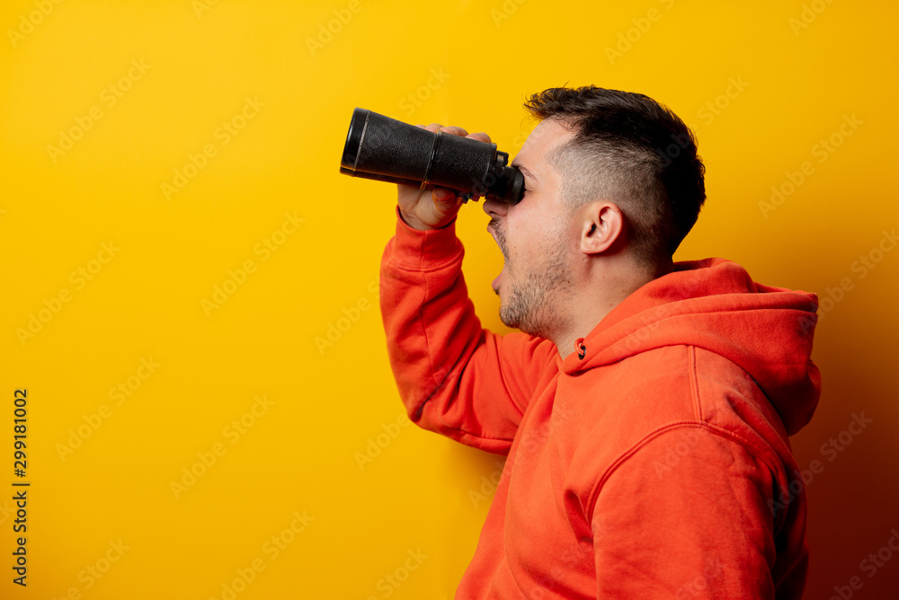 Handsome man with binocular on yellow background Stock Photo | Adobe Stock