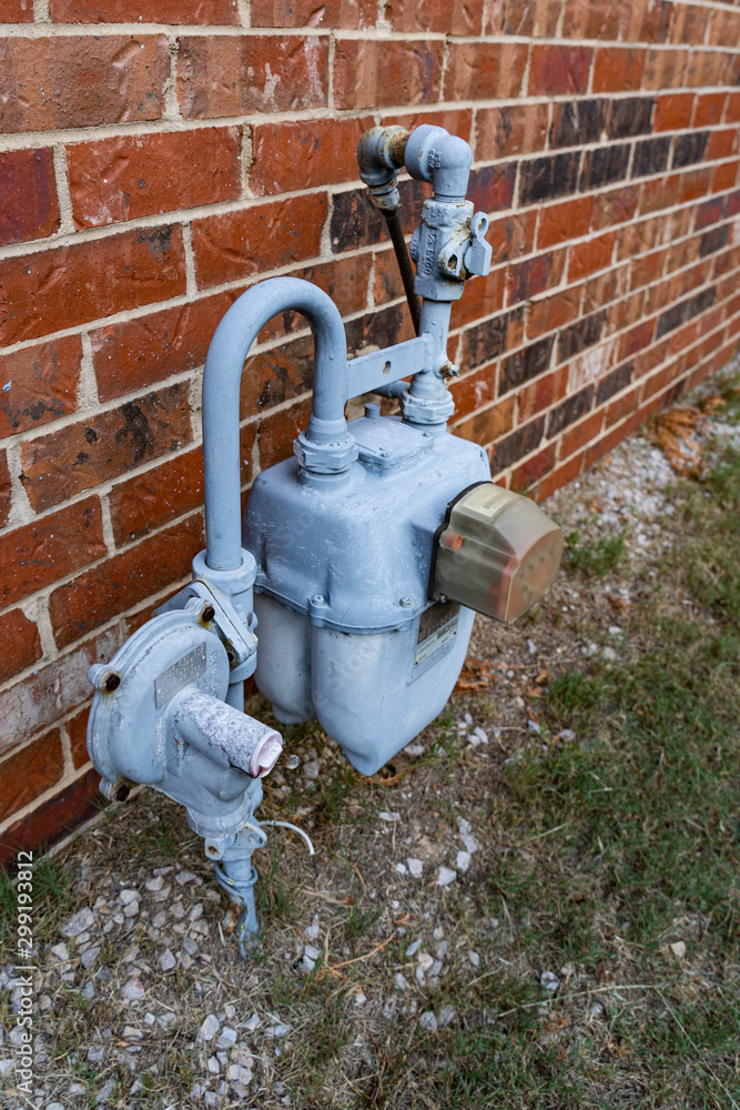 Residential gas meter on the side of a red brick home showing some ...