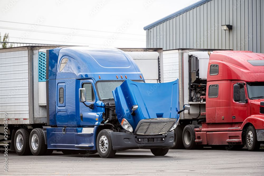 Big rig blue semi truck with open hood standing on the parking lot ...