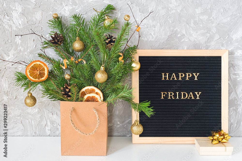 Happy Friday text on black letter board and festive bouquet of fir ...