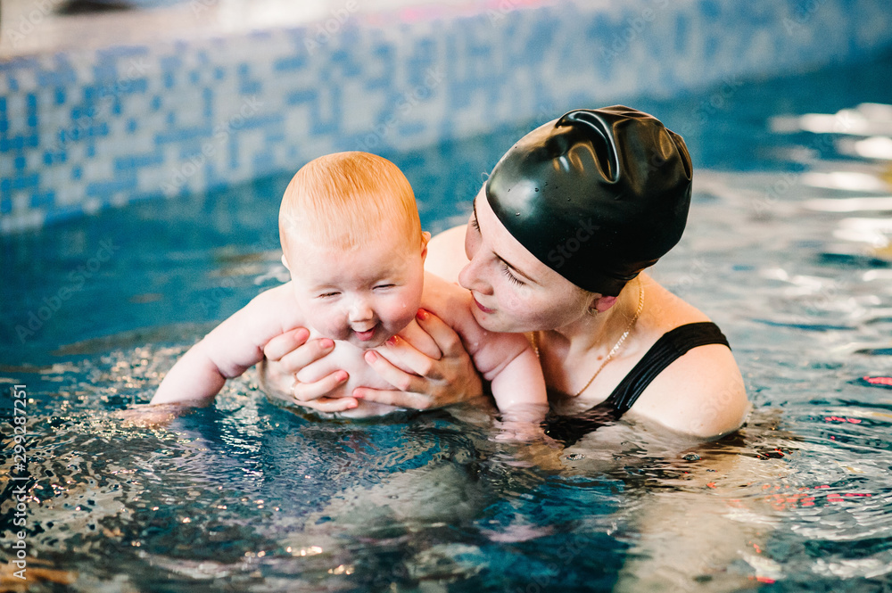 Diving baby in the paddling pool. Young mother, swimming instructor and ...