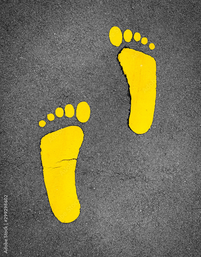 Yellow footprint painted on asphalt road. Walkway lane traffic sign ...