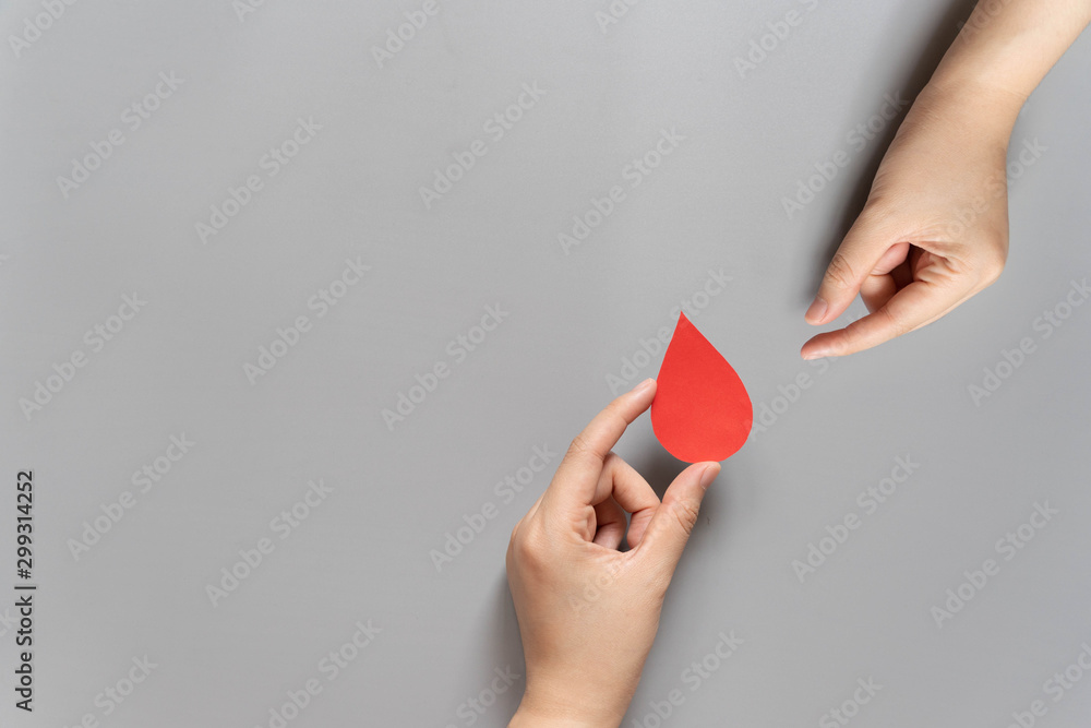 Blood donation - Human hand giving blood drop symbol to a hand on gray ...