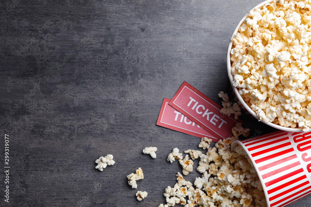 Popcorn and tickets on grey stone table, flat lay with space for text ...