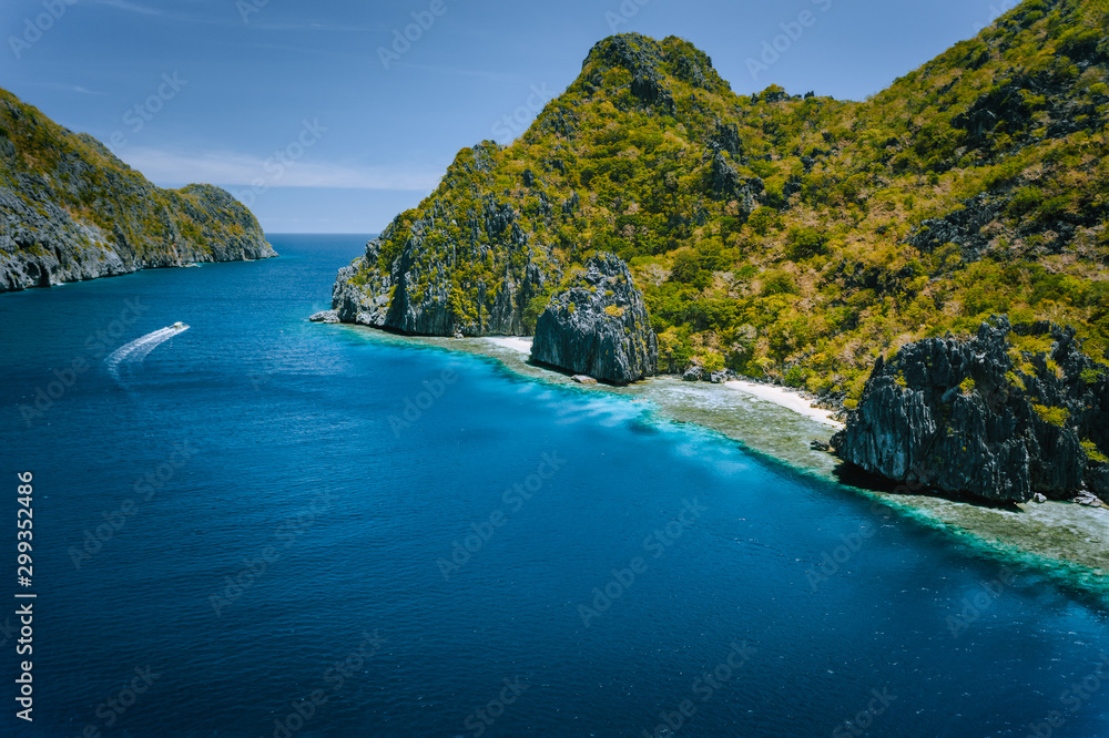 Limestone karst coastline of Matinloc Island with tourist boats in ...